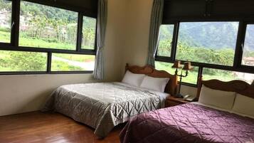 Quarto com duas camas, janelas amplas, piso de madeira e vista para o verde.