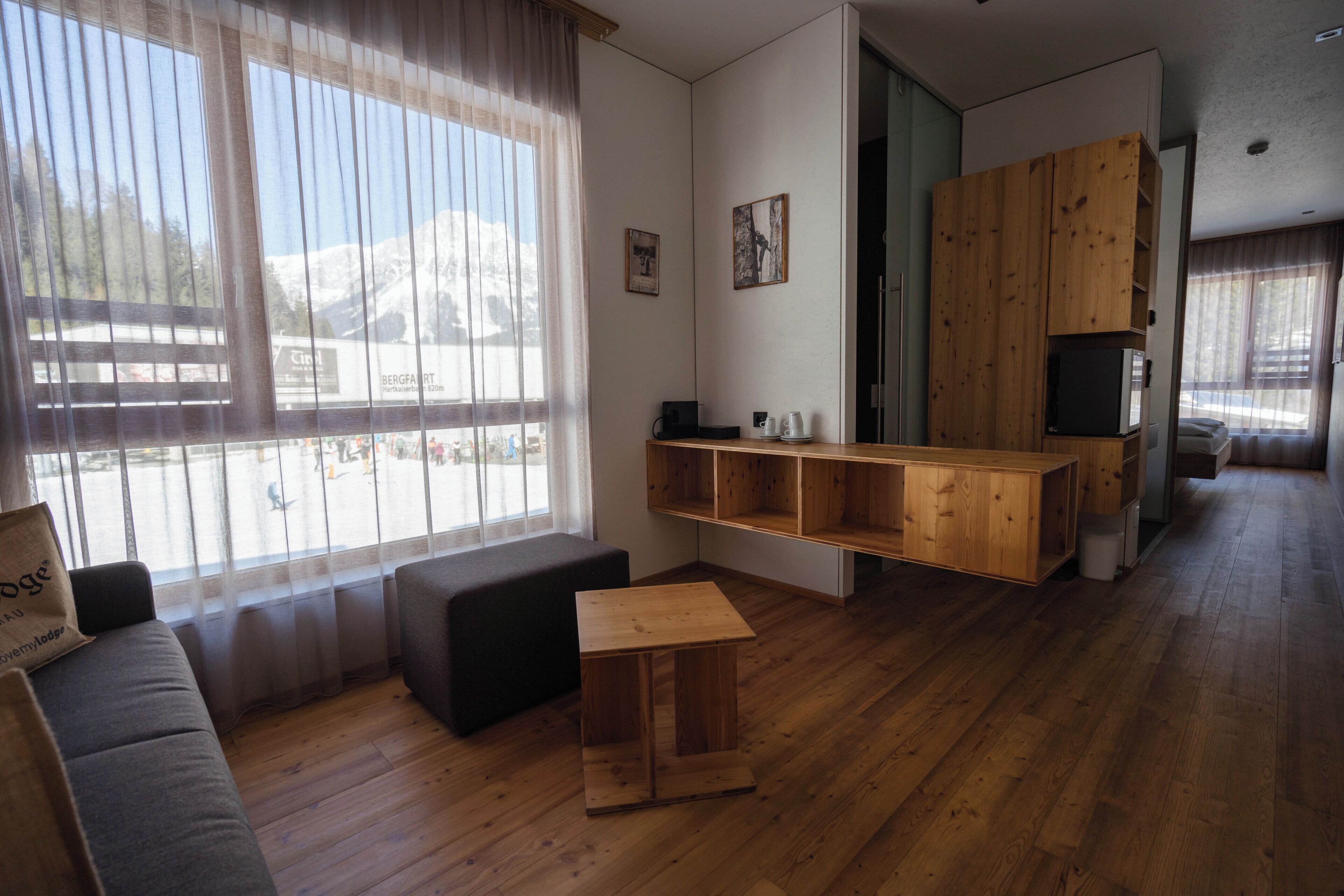Uma sala de estar moderna com piso de madeira, um sofá, uma mesinha e uma televisão.