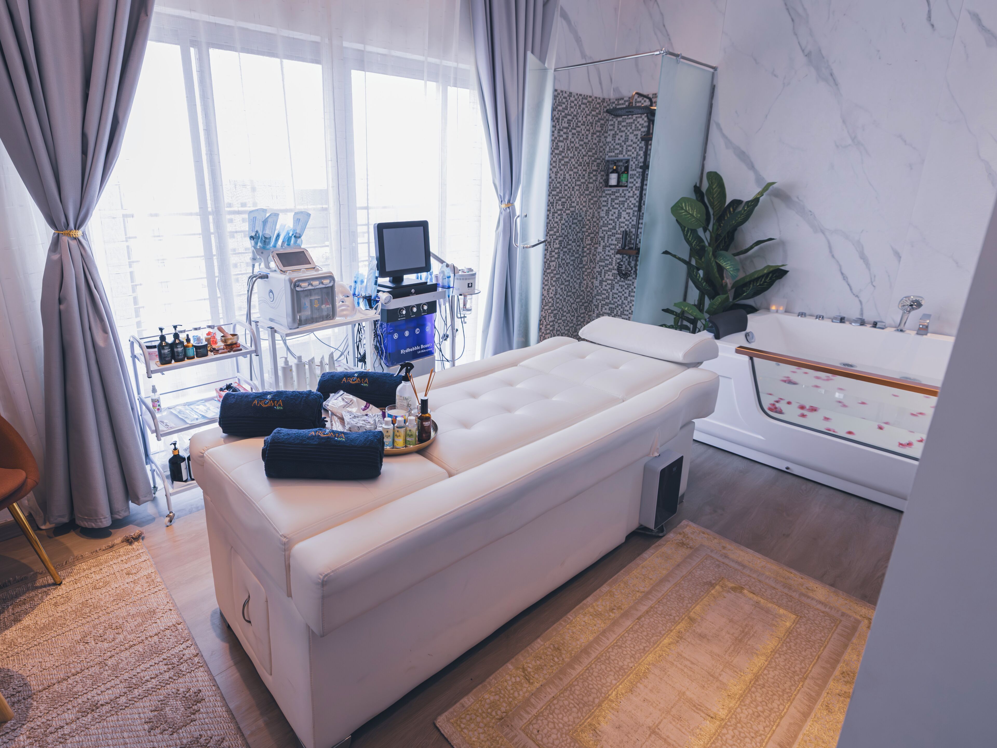 Uma sala de spa moderna com mesa de massagem, banheira e área de chuveiro.