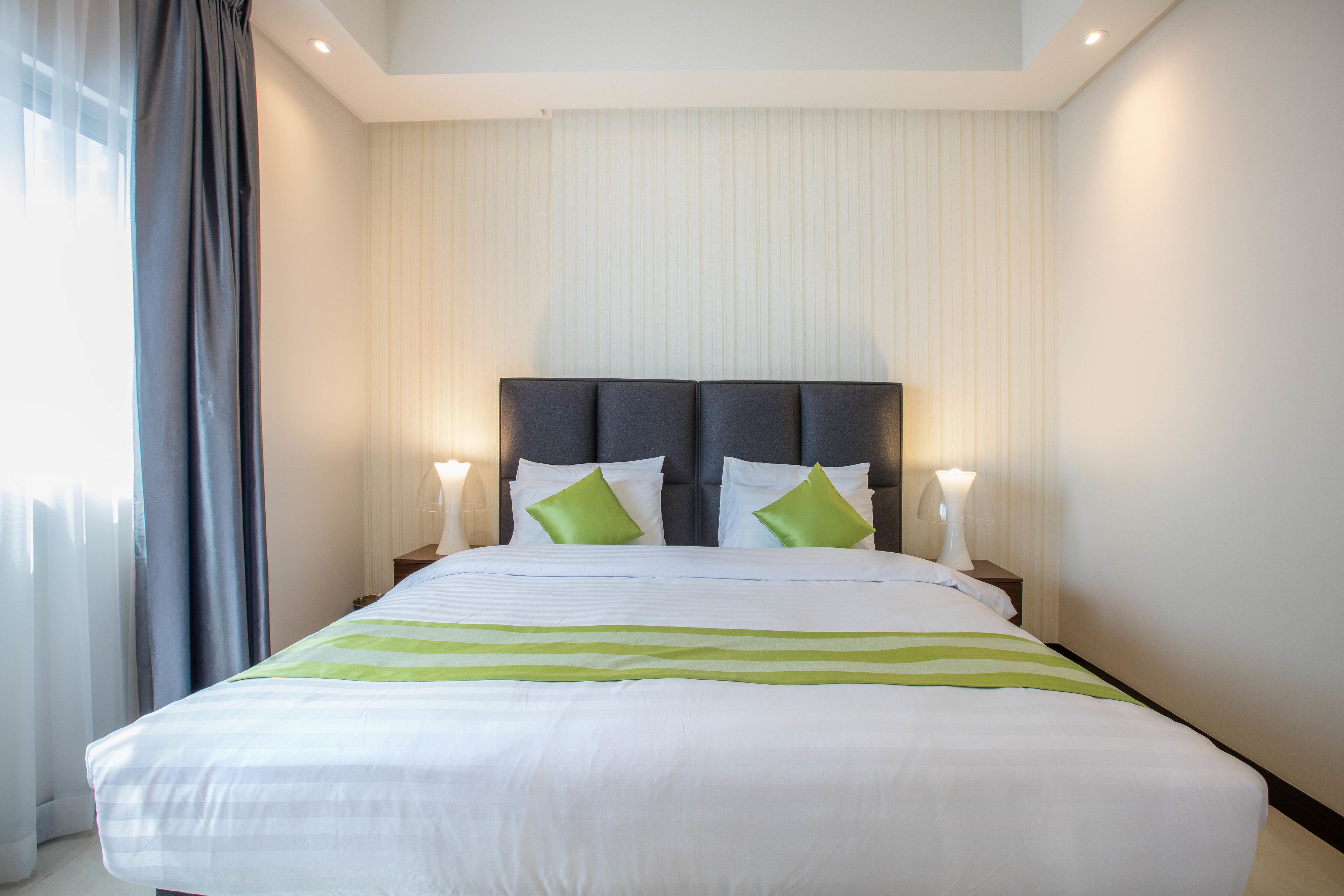Quarto de hotel moderno com uma cama grande, duas mesas de cabeceira e uma cabeceira.