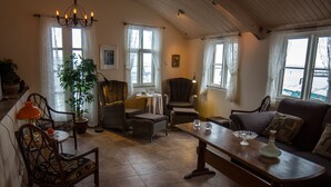 Uma sala de estar aconchegante com móveis de vime, uma mesa de madeira e um lustre.