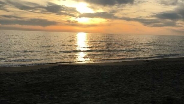 Uma praia com um pôr do sol sobre o oceano.