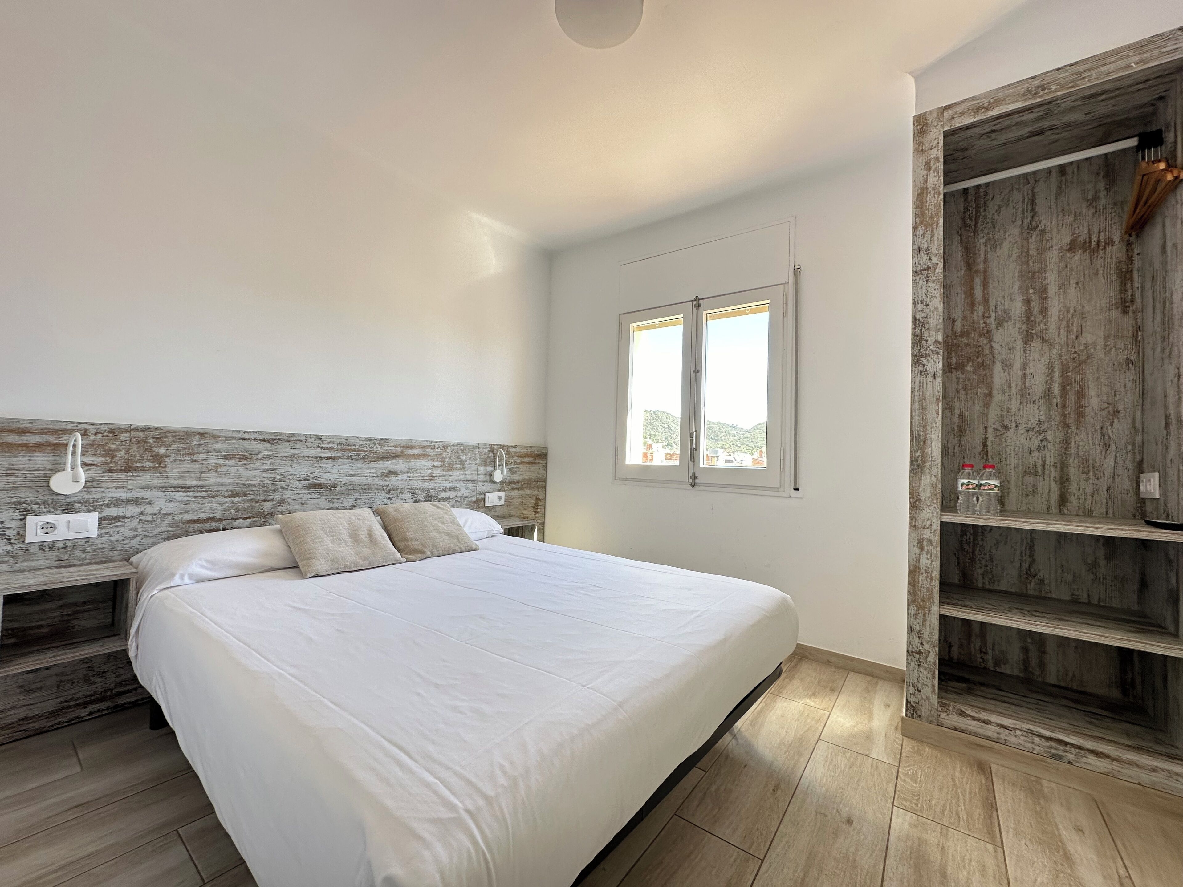 Quarto com uma cama grande, cabeceira de madeira, janela com vista e guarda-roupa de madeira.