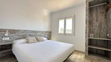 Quarto com uma cama grande, cabeceira de madeira, janela com vista e guarda-roupa de madeira.