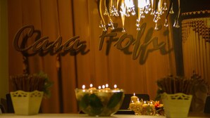 Um quarto iluminado com luz quente, parede de madeira, lustre e um letreiro com a inscrição 'Casa Tof'.