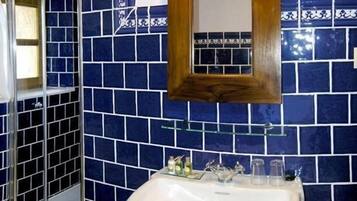 Casa de banho com lavatório, espelho e paredes azulejadas em azul.