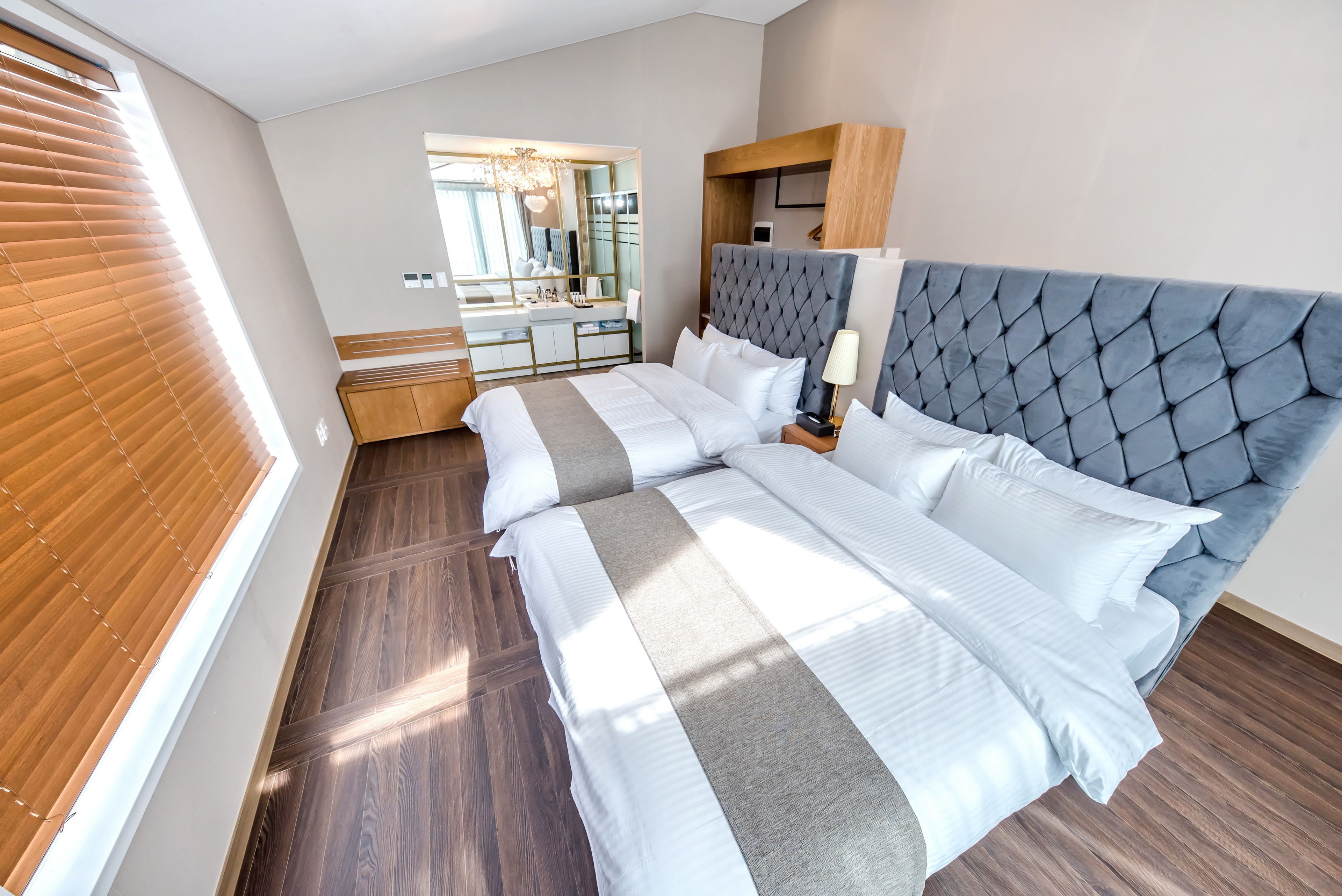 Quarto de hotel com uma cama grande, uma mesa de toucador com espelho e piso de madeira.