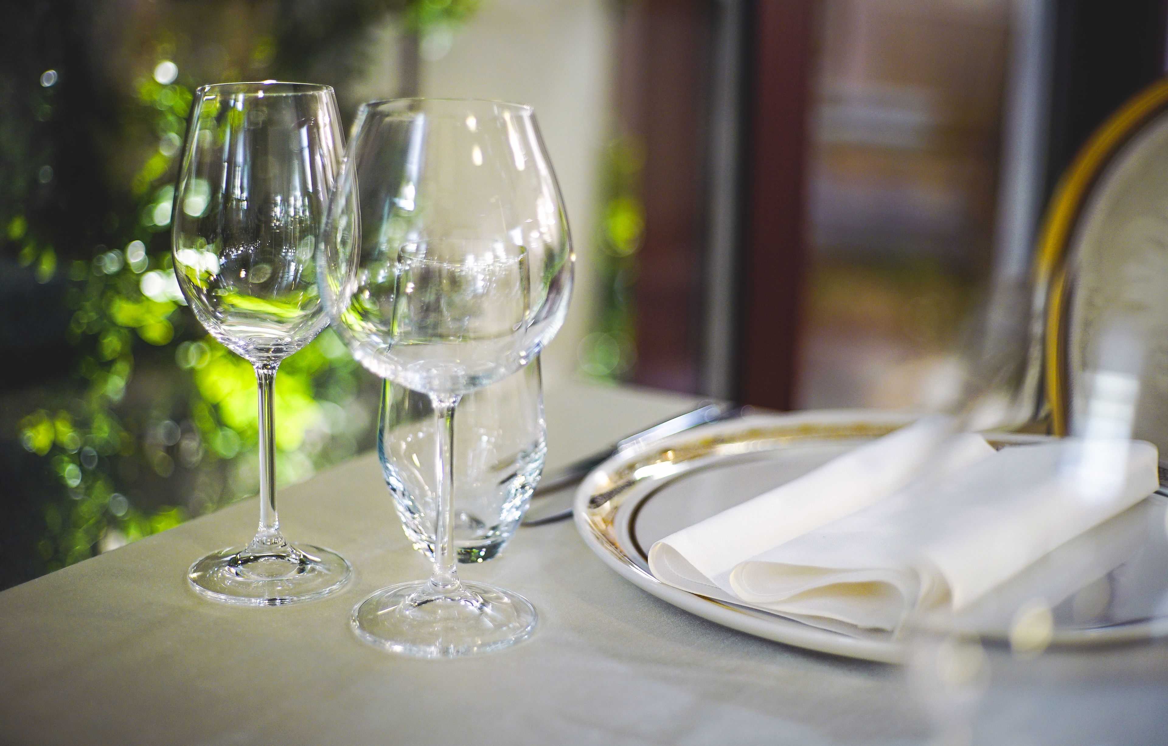 Duas taças de vinho vazias sobre uma mesa com uma toalha dobrada e um suporte de prata.