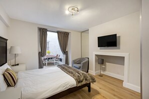 Quarto de hotel moderno com cama, televisão na parede, lareira e vista para o exterior.