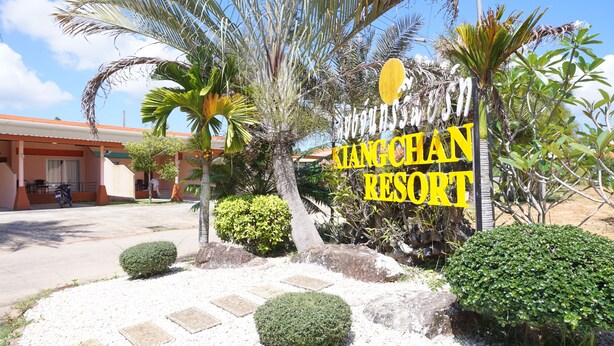 Placa do Shangchan Resort com vista clara da paisagem ao redor, incluindo palmeiras e arbustos bem cuidados.