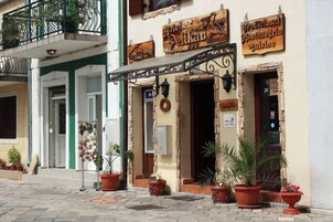 Entrada de hotel com uma placa tradicional, balcão de recepção e plantas em vasos.