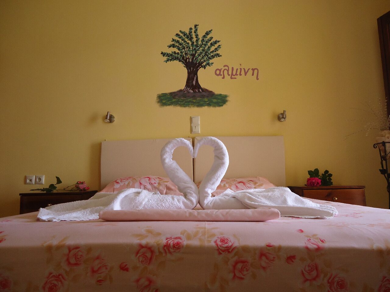 Uma cama com um edredom floral e toalhas dispostas em forma de coração.