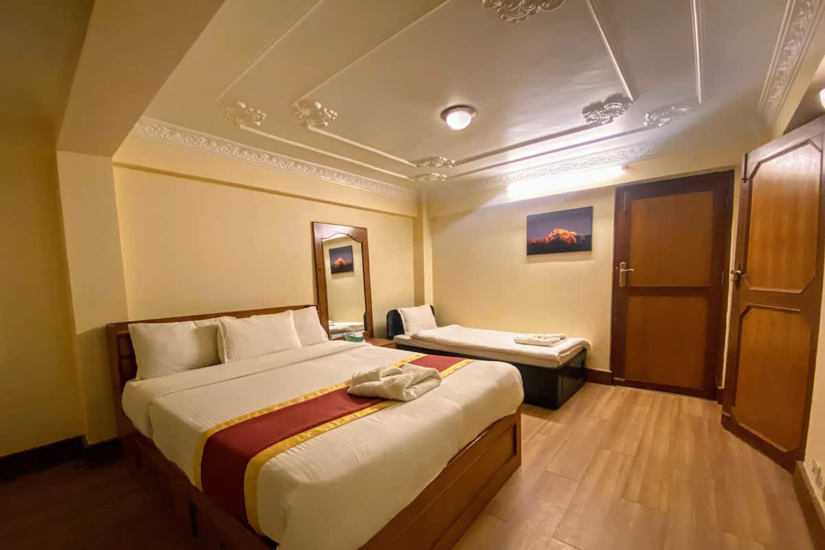 Quarto de hotel com uma cama grande, uma mesa de cabeceira, uma cadeira, um guarda-roupa e um quadro na parede.
