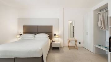 Quarto de hotel moderno com uma cama grande, mesas de cabeceira, um espelho e um guarda-roupa.