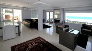 Uma sala de estar moderna com um sofá, uma mesa de centro e um espaço de jantar com uma mesa de vidro.