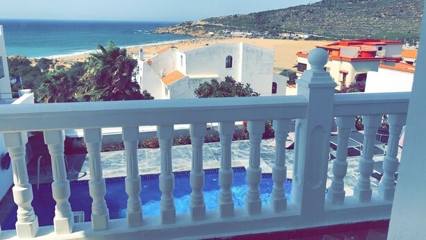 Uma varanda com vista para a praia e uma piscina.