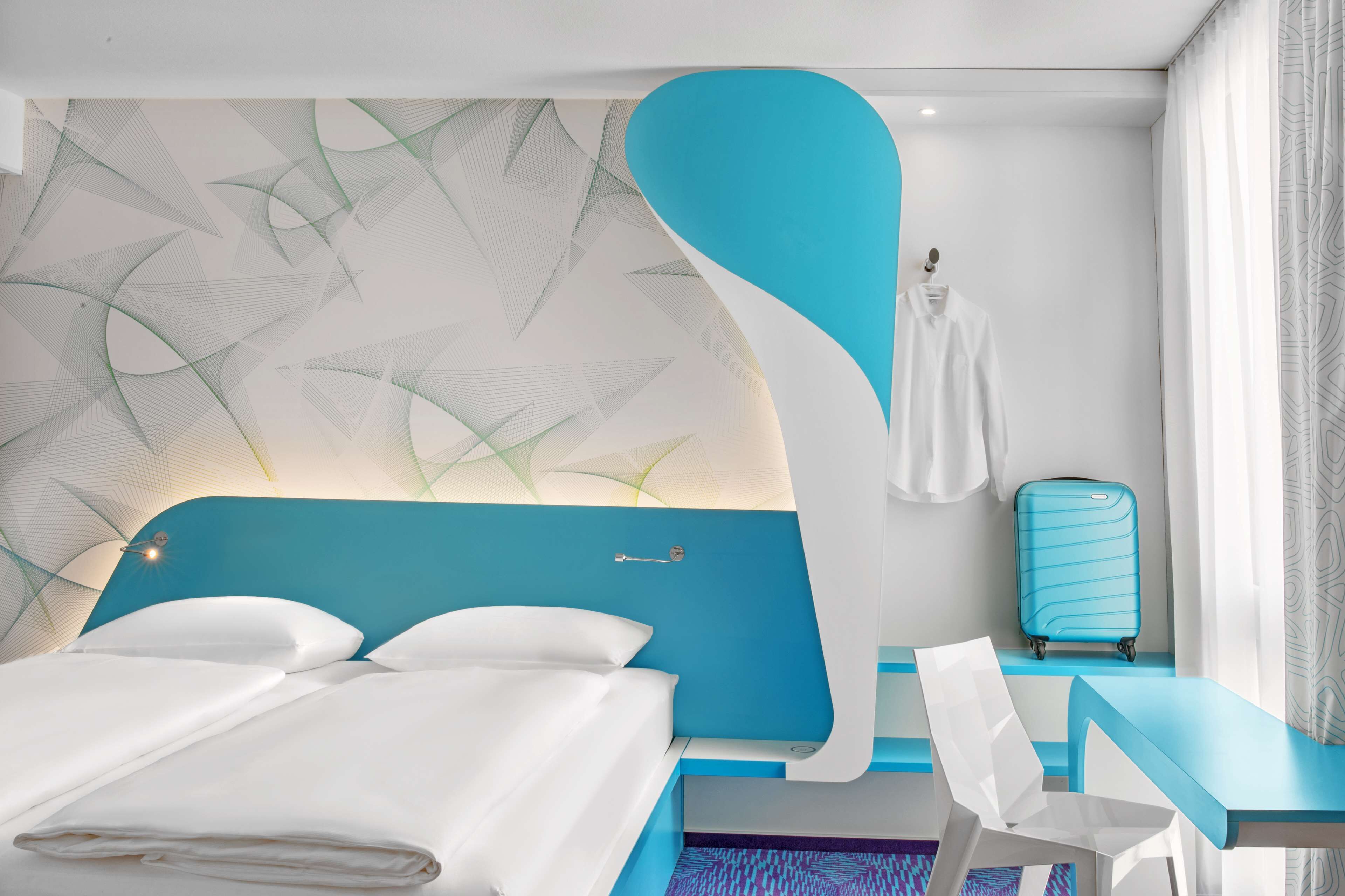 Quarto de hotel moderno com uma cama grande, uma escrivaninha e uma mala.