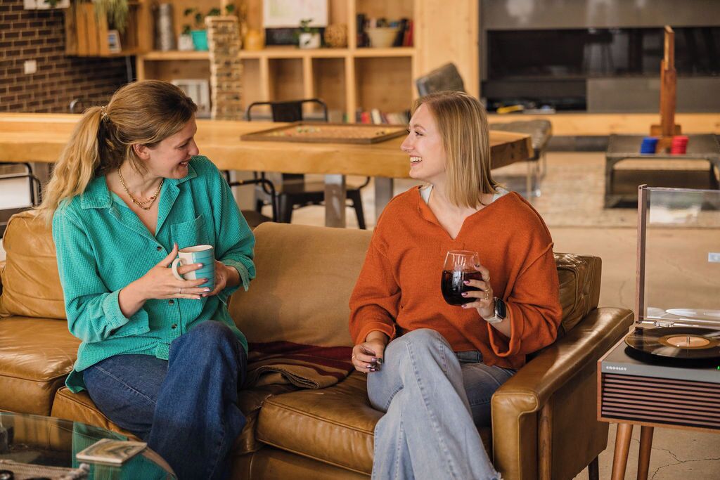 Duas pessoas sentadas num sofá de couro em um interior moderno, com uma mesa de centro e um toca-discos.