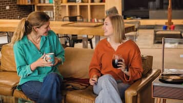 Duas pessoas sentadas num sofá de couro em um interior moderno, com uma mesa de centro e um toca-discos.
