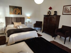 Quarto com uma cama grande, mesa de cabeceira, luminária, cadeira, armário e obras de arte nas paredes.