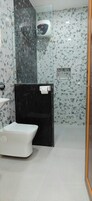 Casa de banho moderna com sanita, cabine de duche com vidro e espelho.