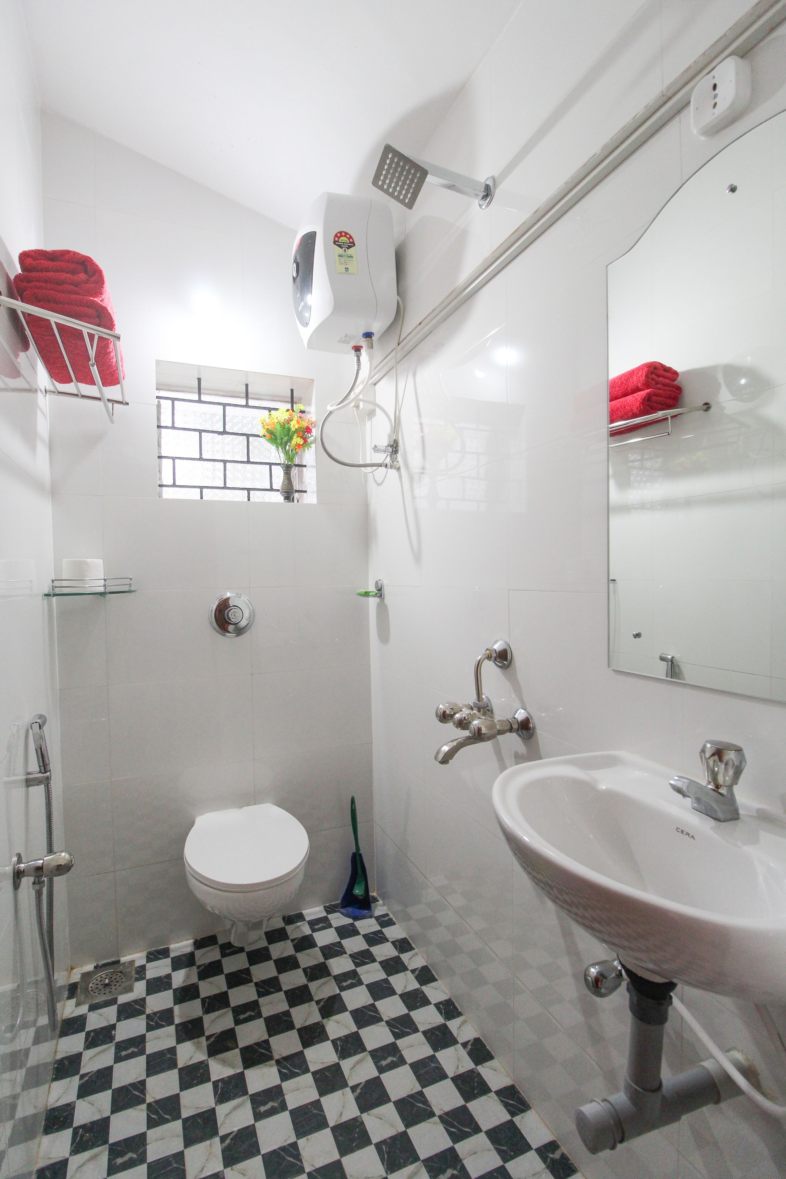Um banheiro com piso xadrez, vaso sanitário, pia e chuveiro.