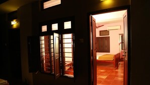Quarto de hotel com cama, escrivaninha e janela com cortinas.