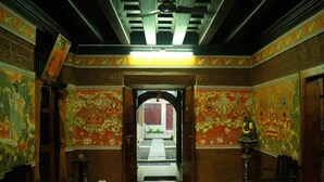 Um corredor ornamentado com piso de azulejos, um tapete vermelho na entrada e uma porta que d á para um quarto.