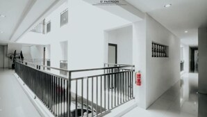 Corredor moderno de hotel com corrimão de metal, um extintor de incêndio e uma escadaria.