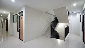 Um interior moderno com escada, paredes brancas e piso revestido de azulejos.