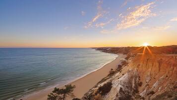 Na praia, praia de areia branca, espreguiçadeiras, guarda-sóis de praia