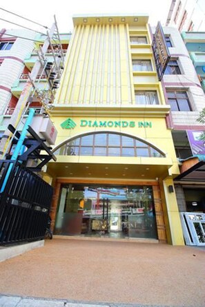 Um hotel chamado 'Diamonds Inn' com fachada amarela, uma grande entrada em arco e varandas visíveis nos andares superiores.