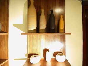 Uma prateleira de madeira com vários vasos e uma mesa de madeira com tapetes enrolados.