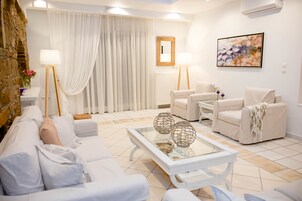 Uma sala de estar moderna com um sofá branco, uma mesa de centro de vidro e duas luminárias de chão.