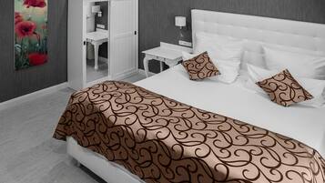 Quarto moderno com uma cama grande, cabeceira branca e manta decorativa estampada.