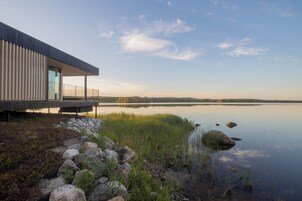 Um edifício moderno com varanda com vista para um lago tranquilo.