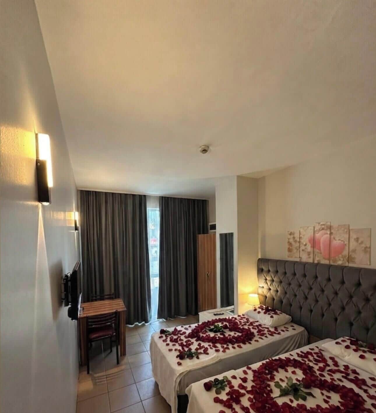 Quarto de hotel com duas camas, uma escrivaninha e vista para o exterior.