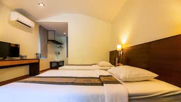 Quarto de hotel com duas camas, televisão, secretária e ar condicionado.