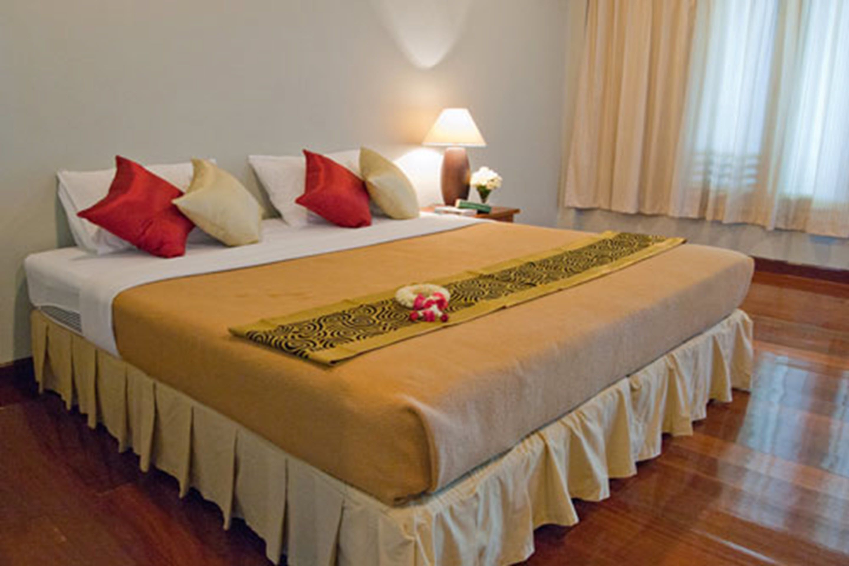 Cama bem arrumada com colcha amarela, almofadas brancas e um cobre-leito decorativo.