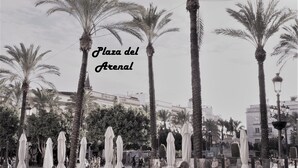 Praça del Arenal com mesas ao ar livre e palmeiras.