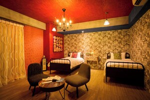 Quarto com duas camas, um candelabro, uma mesa pequena e papel de parede estampado.