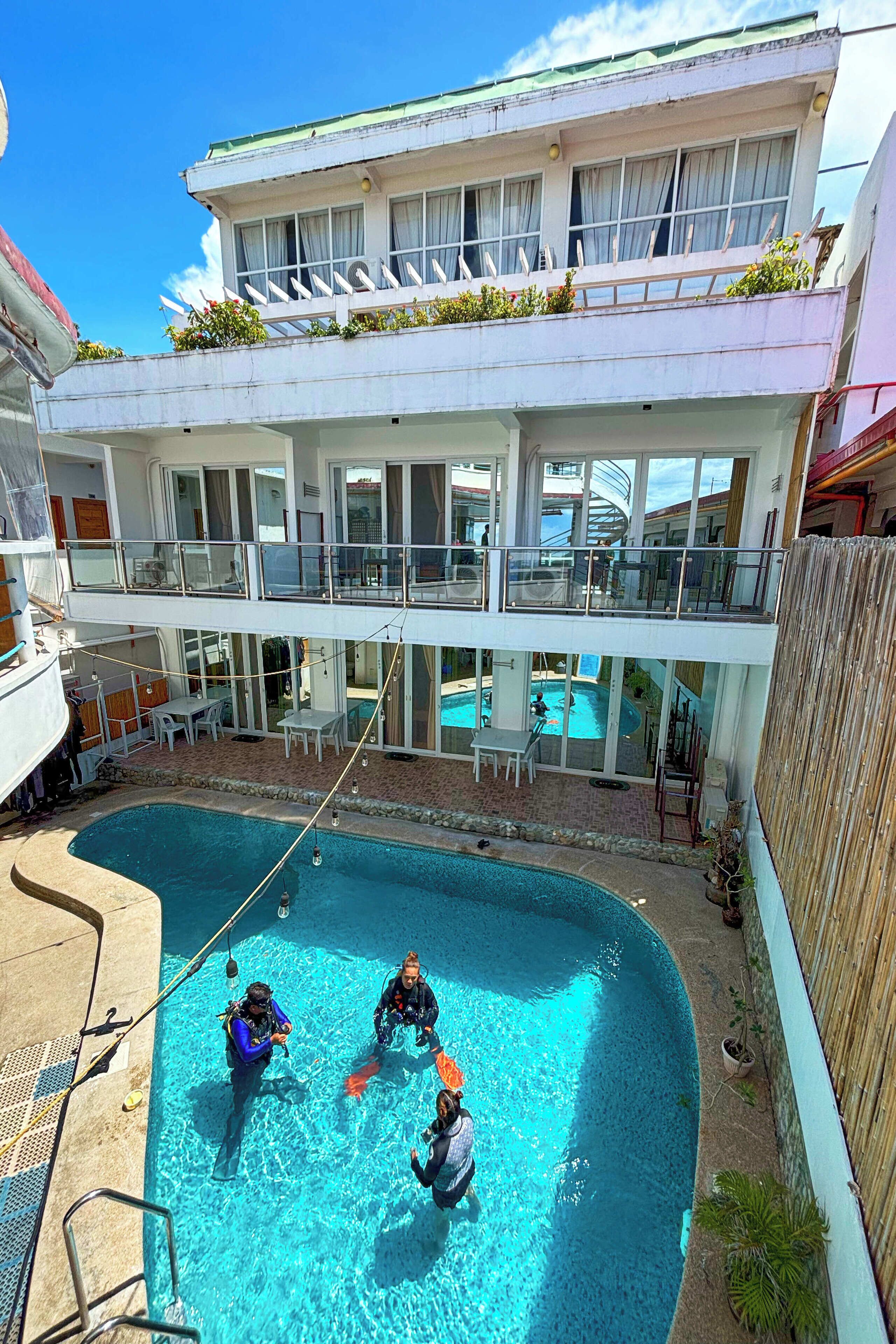 Um edifício de dois andares com piscina no andar térreo.