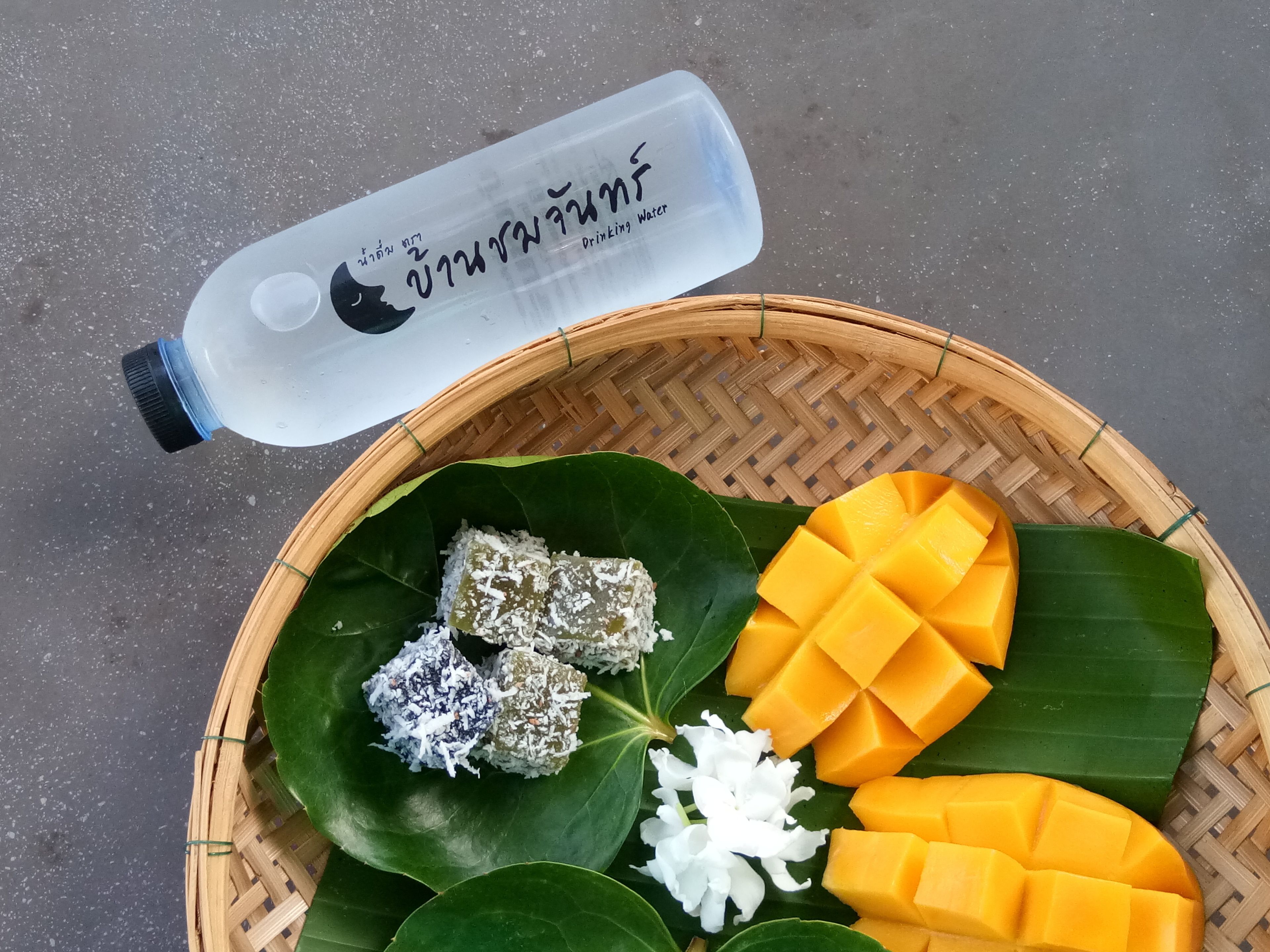 Uma cesta de tecido com alimentos, uma garrafa de água e uma manga.