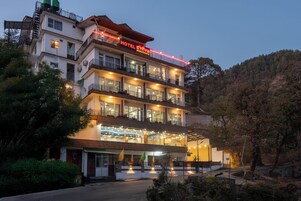 Um hotel com vários andares, varandas, área de refeições e uma placa indicando ser hotel e santuário.