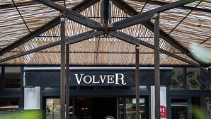 A storefront with a sign reading "VOLVER" and a metal structure above.
