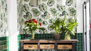 Cozinha com bancada de madeira, painel de azulejos verdes e parede com padrão de folhagem tropical.