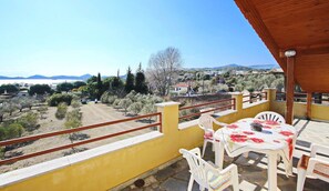 Uma varanda com mesa e cadeiras, com vista para uma paisagem com árvores e edifícios.