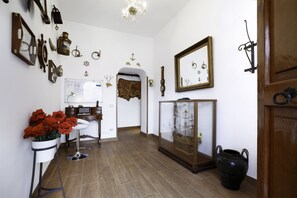 Um corredor com decoração náutica, uma pia branca e um vaso de rosas vermelhas.