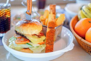 Um prato com um hambúrguer, batatas fritas e uma bebida.
