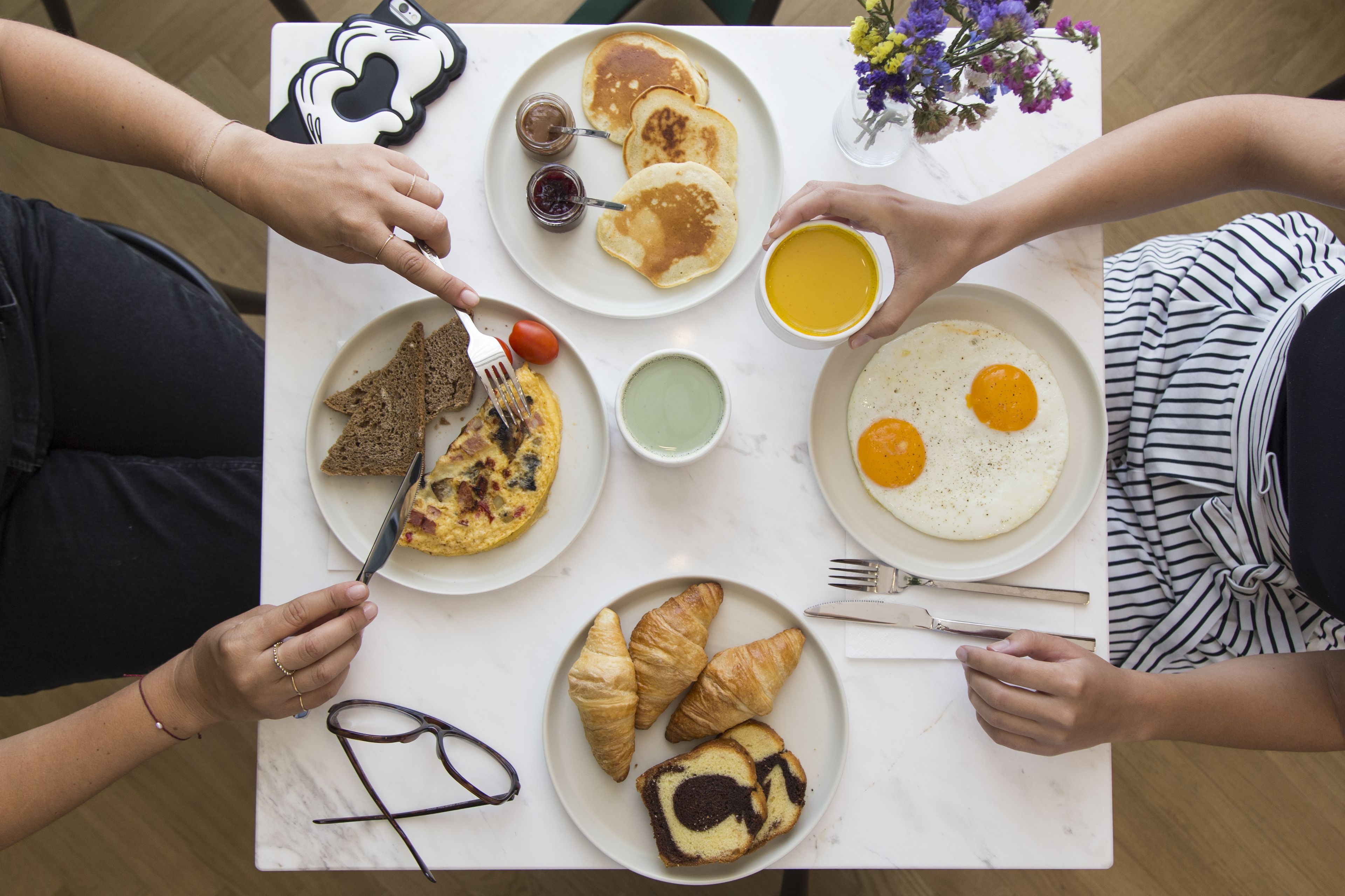 Uma mesa de café da manhã com panquecas, ovos, croissants e torradas.